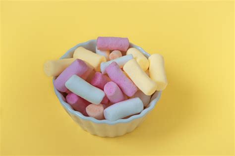 노란색 배경에 그릇에 여러 가지 빛깔의 마시멜로 포장 엽서 또는 카드 클로즈업 상단 보기의 모형 개념과 주제에 대한 스톡 사진
