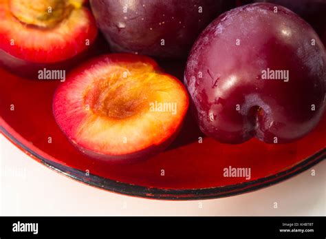 Fresh Plum Fruit With Cut Plum Slices In The Red Saucer On White