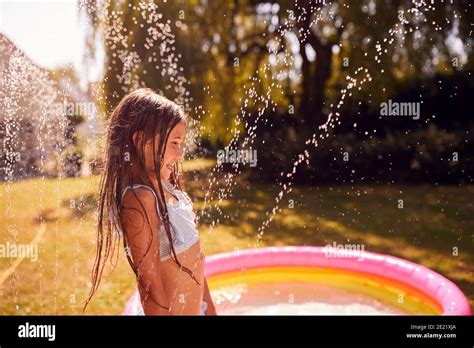 Girl Wearing Swimming Costume Having Fun In Summer Garden Playing In