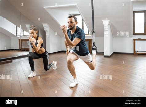 Female Trainer And Man Practising TRX At Gym Suspension Training That Uses Body Weight