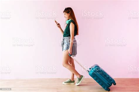 행복 한 젊은 여행자 여자 산책 가방 및 음악 헤드폰 스마트폰 보고 얼굴 및 미소 배경 전체 길이 측면 모습으로 다채로운 파스텔