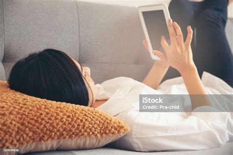 집에서 일하기 위해 휴대 전화를 사용하여 소파에 누워있는 여성 아시아 여성 태블릿을 통해 휴대 전화와 터치 스크린을 들고 기술