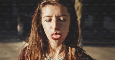 햇볕이 잘 드는 거리에서 혀를 보여주고 웃고 있는 행복한 Boho 평온한 소녀 세련된 보헤미안 소녀가 저녁 여름 도시에서 즐거운 시간을 보내고 있습니다 여름 방학 및