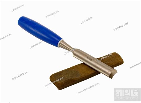Round Metallic Chisel With Plastic Blue Handle On Whetstone Isolated On