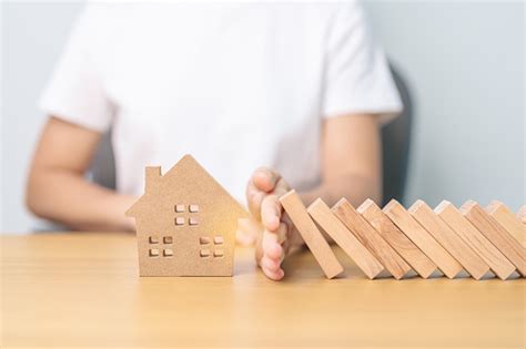 손은 떨어지는 나무 블록을 멈추고 집 모델을 보호합니다 위기 가을 비즈니스 위험 경기 침체 개발자 부동산 및 부동산 개념 파산에