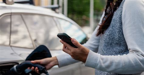 한 여성이 전기 충전기로 자동차를 충전하고 있습니다 사진 Unsplash의 지속가능성 이미지