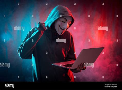 Hacker With An Anonymous Mask With A Computer And Making A Fight Symbol