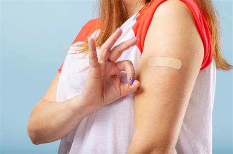 성공적인 Covid19 예방 접종 예방 접종 을 받은 여성은 백신 주사 후 접착제 붕대로 팔을 보여주고 있습니다 Covid19