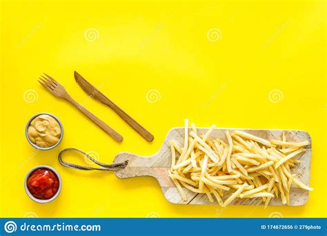 French Fries Served On Cutting Board On Yellow Table Top Down Copy