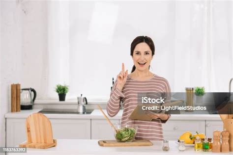 신선한 채소와 함께 테이블에 서서 영수증을 들고있는 동안 매력적인 미소 여자 는 아이디어 기호를 보여주는 가구에 대한 스톡 사진