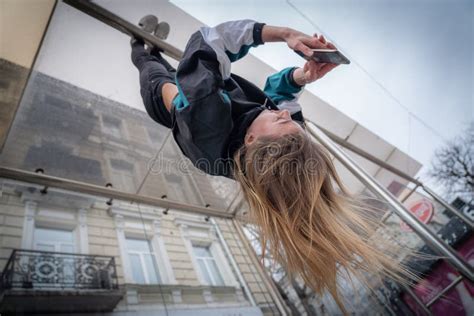 Girl Hanging By Feet Upside Down In The Street And Reading Book