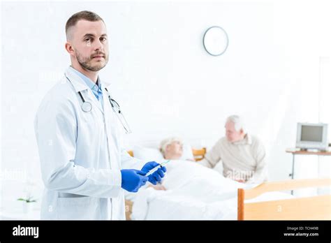 Doctor In Latex Gloves Holding Syringe Ill Patient And Senior Man In