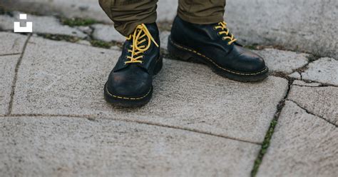 갈색 바지와 검은 가죽 신발을 신은 사람이 회색 콘크리트 바닥에 서 있습니다 사진 Unsplash의 무료 스타일 이미지