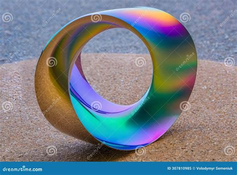 Colorful Mobius Strip With Chrome Effect Displayed On A Sandy Surface