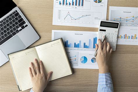 한 사업가가 흰색 계산기를 누르고 재무 부서 회의에서 메모한 노트북의 숫자를 살펴보고 보고서의 숫자의 정확성을 확인합니다 금융 컨셉 가격에 대한 스톡 사진 및 기타 이미지