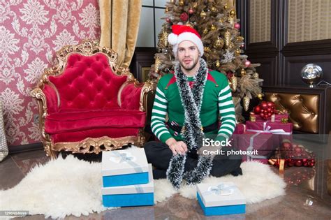 선물 상자와 산타 모자에 남자 크리스트맨 나무에서 산타 클로스 의상을 입은 남자 남자는 크리스마스와 새해를 축하합니다 산타 클로스는 Xmas와 새해를 준비합니다