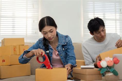 Preparation And Execution A Young Woman Meticulously Packages Items While Her Partner Prepares