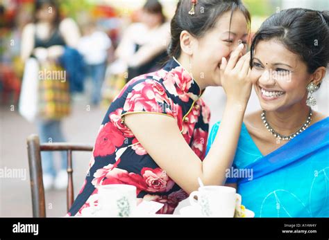 Close Up Of A Young Woman Whispering Into Another Womans Ear Stock