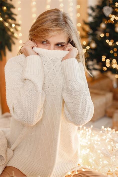 Portrait Of A Blonde Woman Covering Her Face In White Sweater Stock