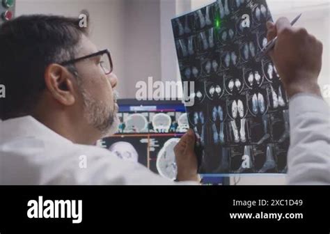 Close Up Shot Of Middle Aged Multiethnic Radiologist Holding Feet X Ray