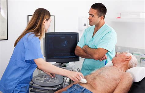 현대 초음파 기계로 환자를 검사하는 두 명의 자신감 있는 초음파 검사자가 함께 일합니다 감정에 대한 스톡 사진 및 기타 이미지 감정 건강관리와 의술 긍정적인 감정