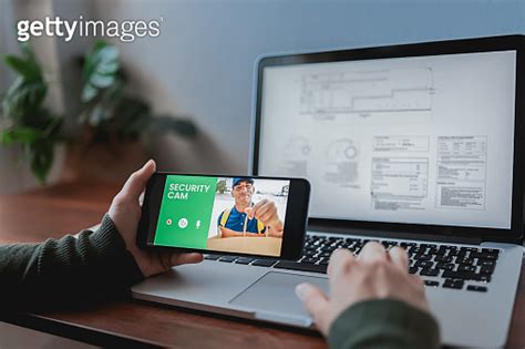 Woman Monitoring Delivery Man Ringing Door Bell With Cctv Safety Camera On Mobile Phone Home