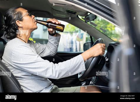 Drunk Asian Young Man Drives A Car With A Bottle Of Beer Dangerous