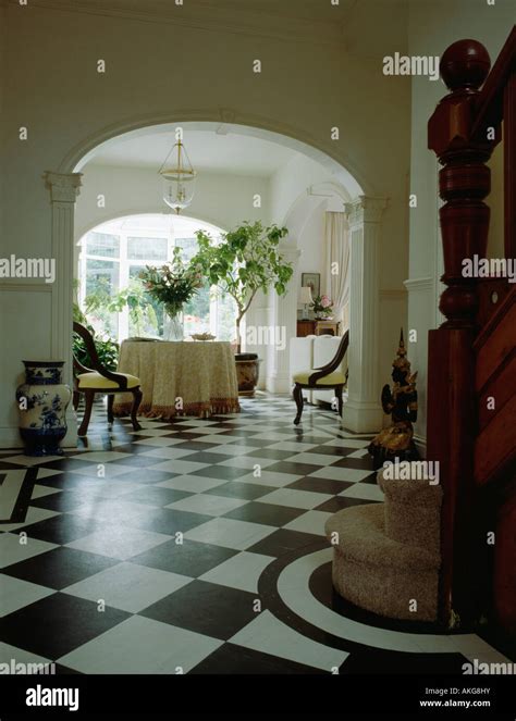 Black And White Vinyl Chequerboard Flooring In Traditional Hall With View Of Dining Room Through