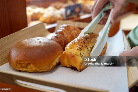 베이커리 가게에서 페이스트리를 고르고 쟁반을 들고 집게를 사용하는 여성의 클로즈업 고름에 대한 스톡 사진 및 기타 이미지