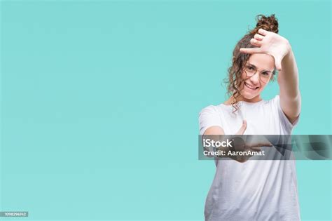 아름 다운 젊은 갈색 머리 곱슬 머리 소녀 미소 행복 한 얼굴로 손가락과 손으로 만드는 프레임 격리 된 배경 위에 안경을 쓰고 창의력과 사진 개념입니다 개념에 대한 스톡