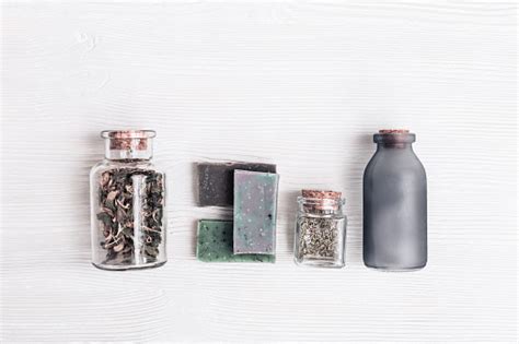 향기로운 허브와 천연 유기농 Diy 성분이있는 천연 비누 바가있는 작은 유리 병이있는 평평한 평신도 조성 아로마 테라피 뷰티 스파 배경 흰색 나무에 목욕 액세서리에 최고