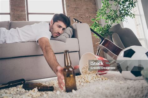 바닥에 맥주 병 팝콘을 복용 소파 누워 혼합 경주 술남자의 사진은 파티 숙취 아침 두통 지저분한 평면 실내 후 고통 미친