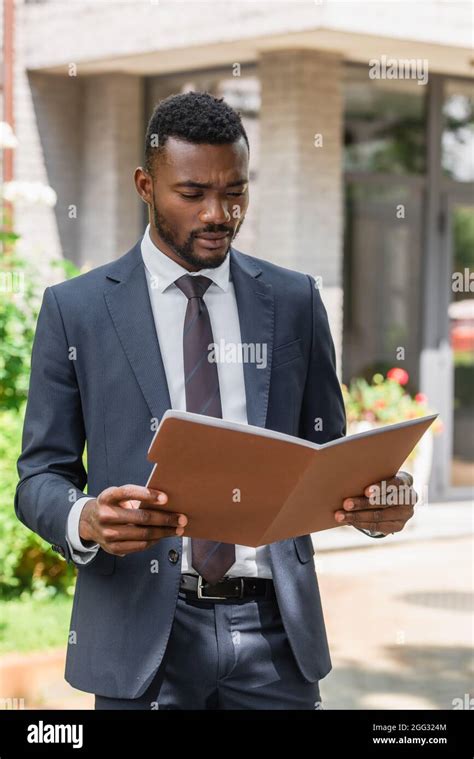 Focused African American Businessman Holding Folder Outside Stock Photo