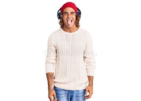 Young Hispanic Man Listening To Music Using Headphones Sticking Tongue