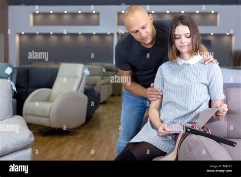 Husband And Wife In Process Of Choosing Upholstery Fabric From Catalog