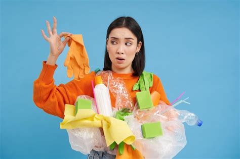 젊은 여자 보유 플라스틱 쓰레기 R에 대 한 쓰레기를 정렬 하는 충격된 얼굴 냄새 나는 쓰레기와 장갑에 보이는 무료 사진