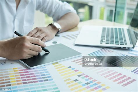 컴퓨터와 색상 견본 작업 젊은 그래픽 디자이너 현대 사무실에서 스타일러스 펜과 디지털 태블릿을 사용 하 여 창조적인 사람 작업 도구와 샘플 컬러 카탈로그를 사용 하 여