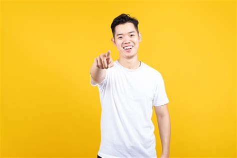 매력적인 초상화 행복 한 젊은 아시아 남자 미소 웃고 카메라를 가리키는 복사 공간 노란색 배경 고립 된 스튜디오 샷에 흰색