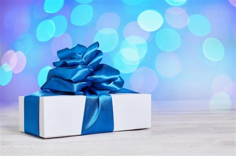 Caja de regalo con un clásico lazo azul sobre un fondo con fondo desenfocado bokeh Foto Premium