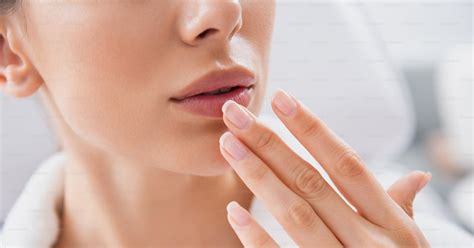 건강 및 얼굴 치료 그녀의 부드러운 봉제 입술을 부드럽게 만지는 젊고 신중하고 우아한 여성의 잘린 얼굴 초상화를 닫습니다