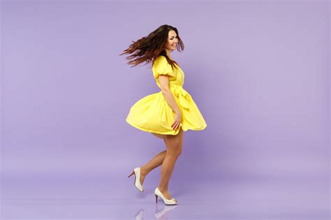 여름 노란색 드레스에 쾌활 한 젊은 여자는 스튜디오에서 파스텔 바이올렛 배경에 고립 옆으로 찾고 머리를 끼고 소용돌이 사람들은 진심으로 감정 라이프 스타일 개념입니다 복사