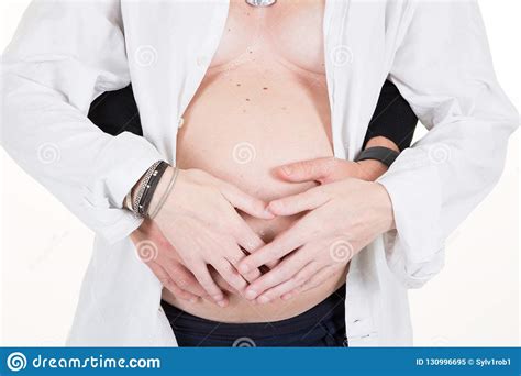 Pregnant Woman And Her Handsome Husband Hugging The Tummy In White