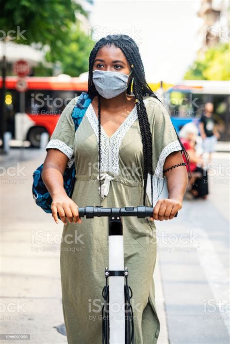 보호 얼굴 마스크를 착용하고 도시를 운전하기 위해 전기 스쿠터를 사용하는 젊은 여성 20 24세에 대한 스톡 사진 및 기타