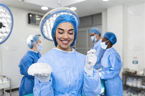 整形外科医生在外科室内拿着硅胶乳房植入物。整容手术的概念