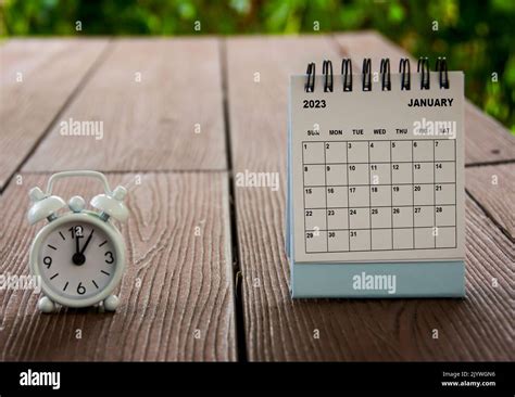 Alarm Clock Pointing At 1 Oclock With January 2023 Calendar On A Bench