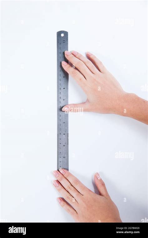 Two Hands Of A Man Holding A Ruler To Measure Something In White