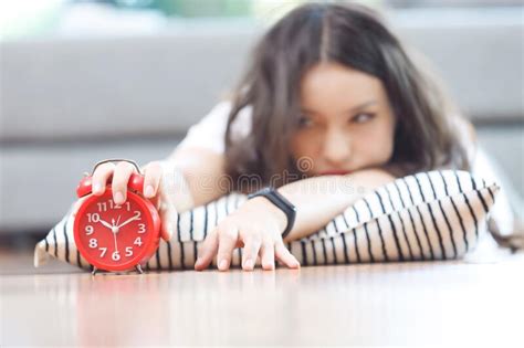 asian woman turning off alarm clock while sleepy on holidays girl is