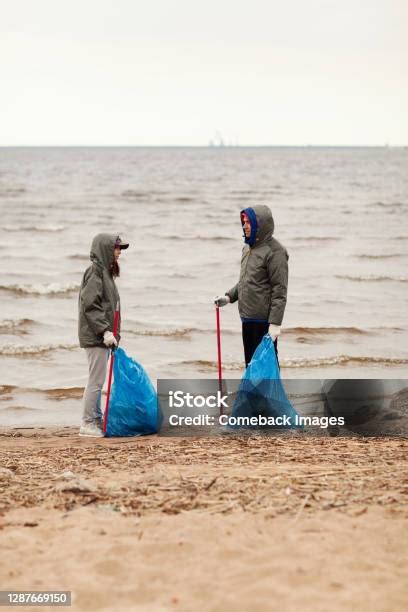 쓰레기 피커와 비닐 봉지를 사용하여 해변을 청소하는 동안 두 명의 환경 자원 봉사자 젊은 남자와 여자 이야기 30 34세에 대한 스톡 사진 및 기타 이미지 Istock