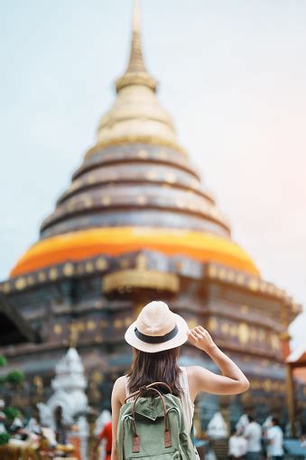 모자와 가방을 들고 하얀 드레스를 입은 젊은 아시아 여성 여행자가 왓 프라 탓 람팡 루앙에서 관광객을 방문하고 있다 아시아 여행 람빵에 대한 스톡 사진 및 기타 이미지