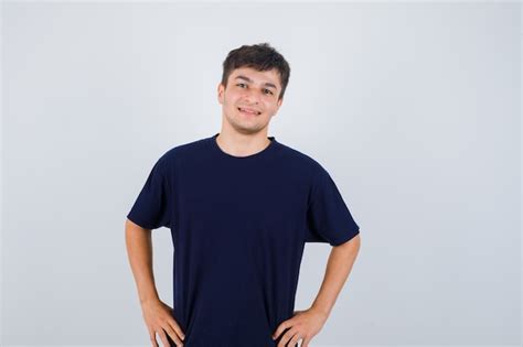 갈색 머리 남자 T 셔츠에 허리에 손을 포즈와 쾌활 한 전면보기를 찾고 무료 사진